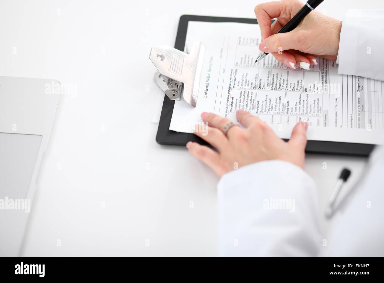 Close-up of a female doctor filling out application form , sitting at ...