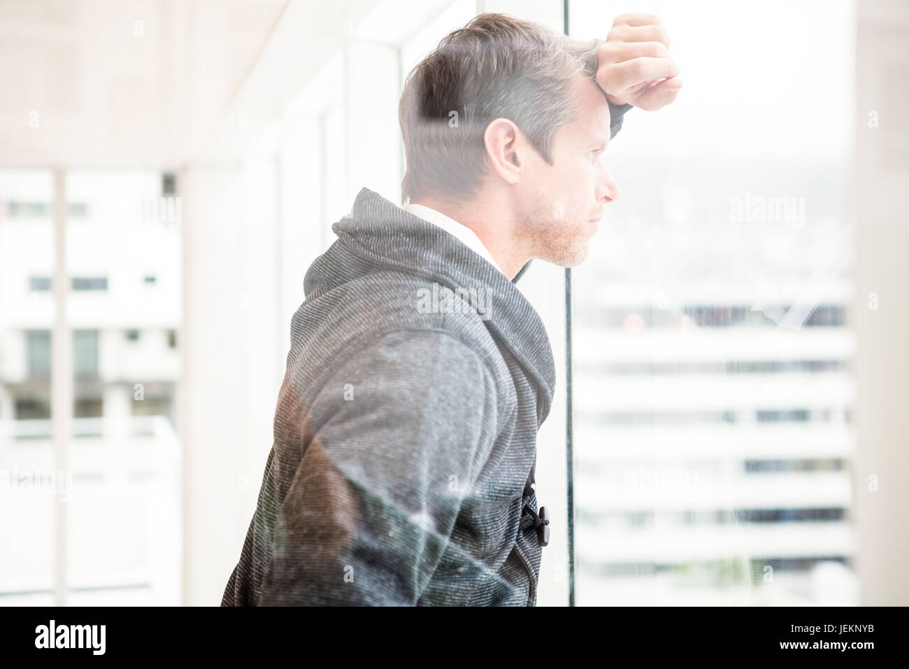 Thoughtful man leaning on glass window Stock Photo - Alamy