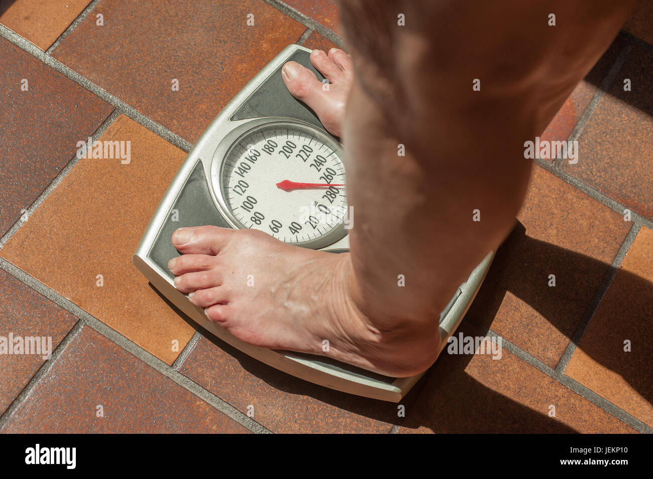 A severely overweight person weighing herself or himself on a bathroom ...
