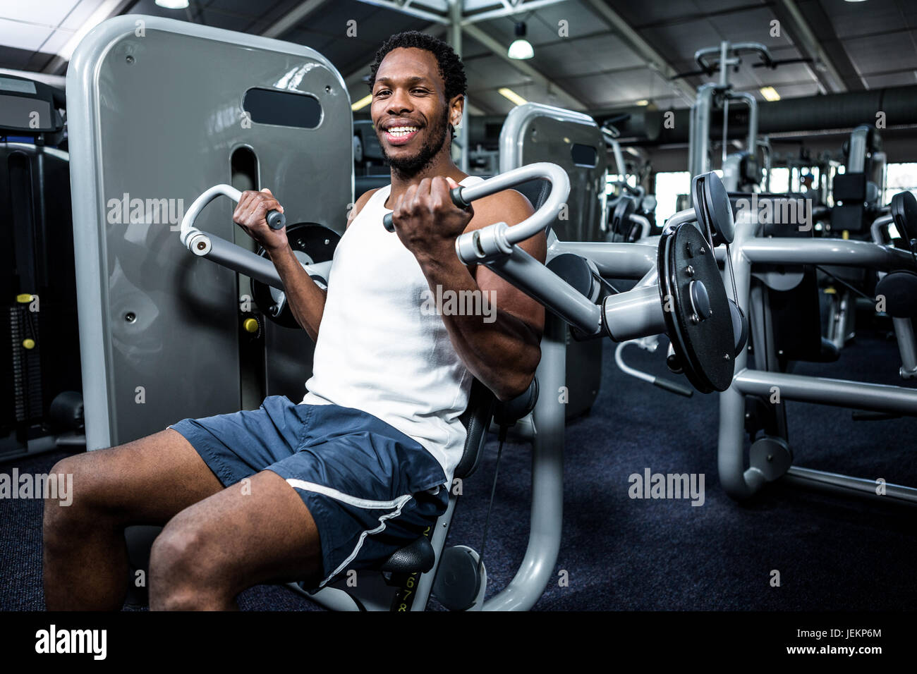 Smiling muscular man using exercise machine Stock Photo - Alamy