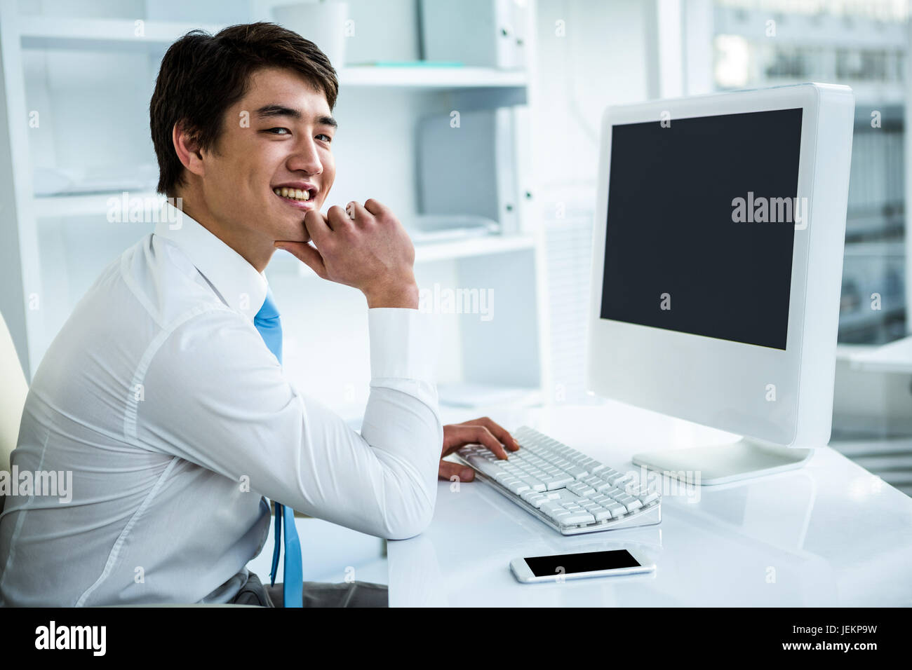 Smiling asian businessman using his computer Stock Photo - Alamy