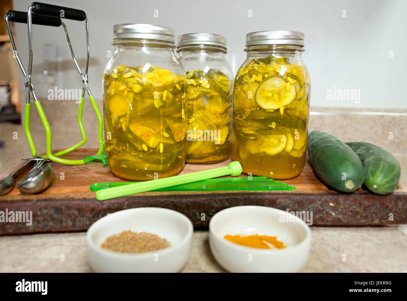 Pickles in Jars sitting on a Cutting Board on a Kitchen Counter along ...