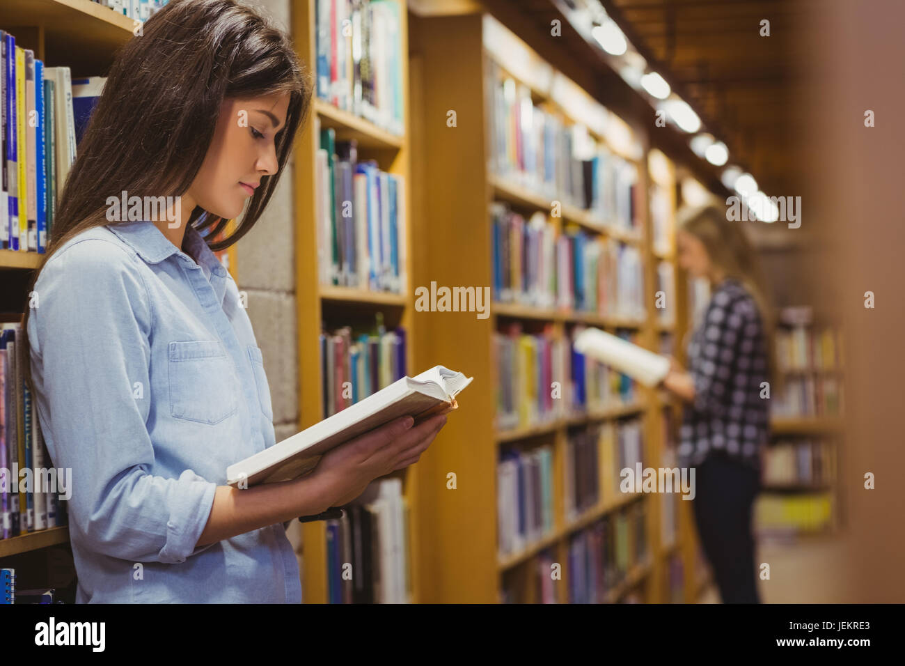 Serious students reading next to bookshelf Stock Photo - Alamy