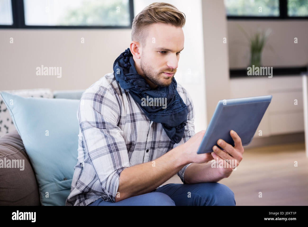 Handsome man using tablet on the couch Stock Photo - Alamy