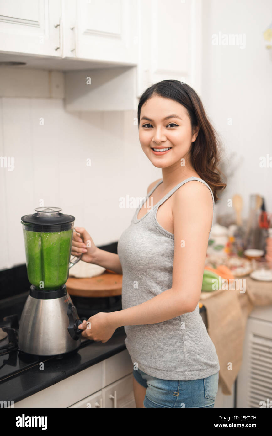 Smiling Asian Woman Making Smoothie With Fresh Vegetables In The