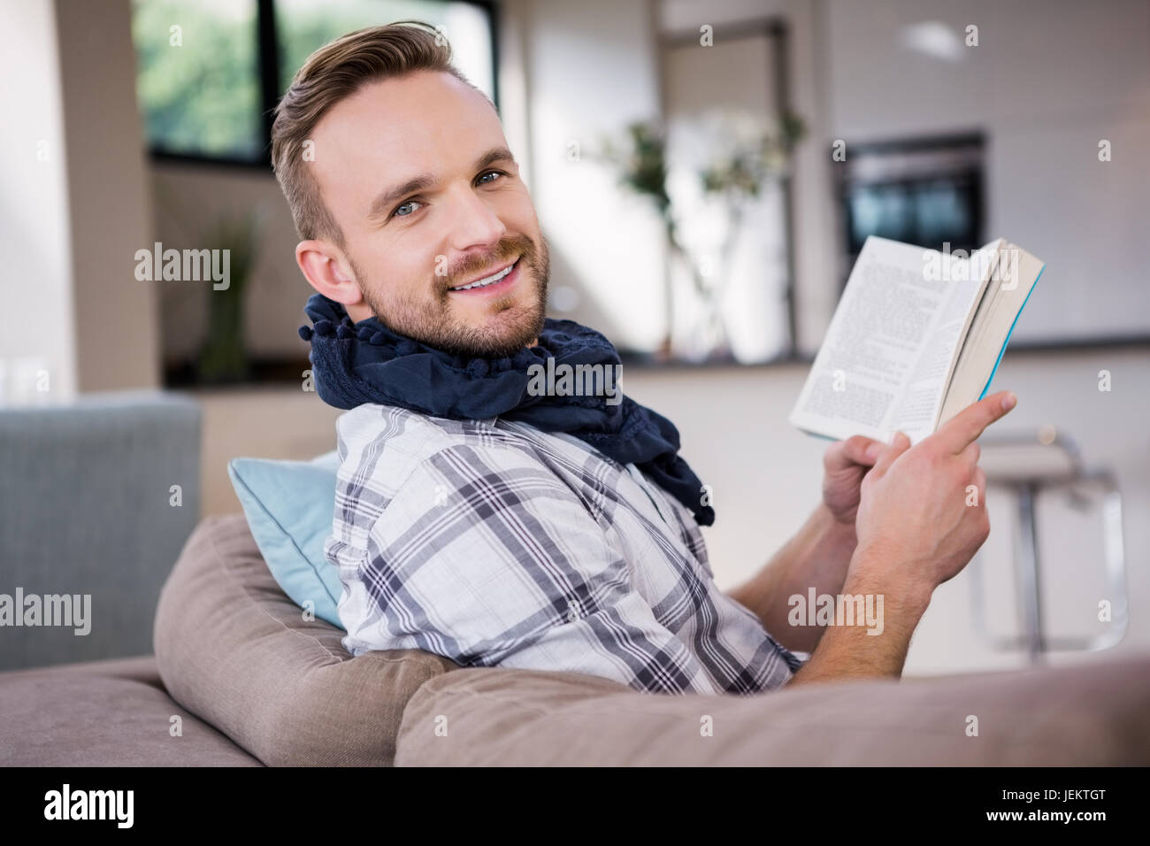 Handsome man reading a book on the couch Stock Photo - Alamy