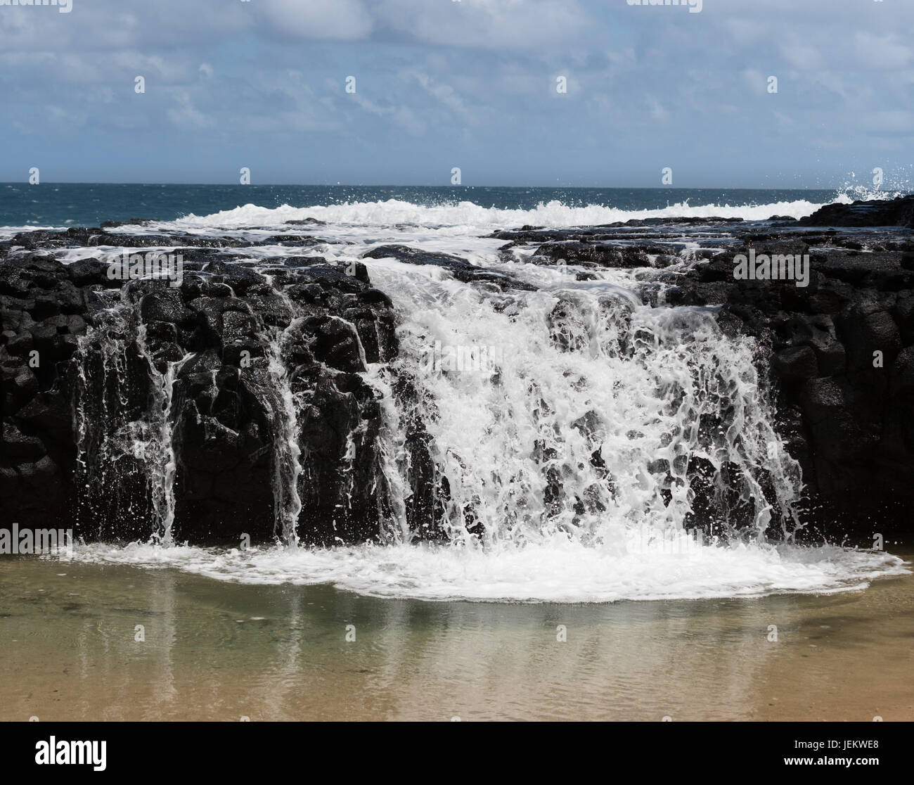 Frozen motion of ocean waterfall over rocks at Lumahai Beach Stock ...