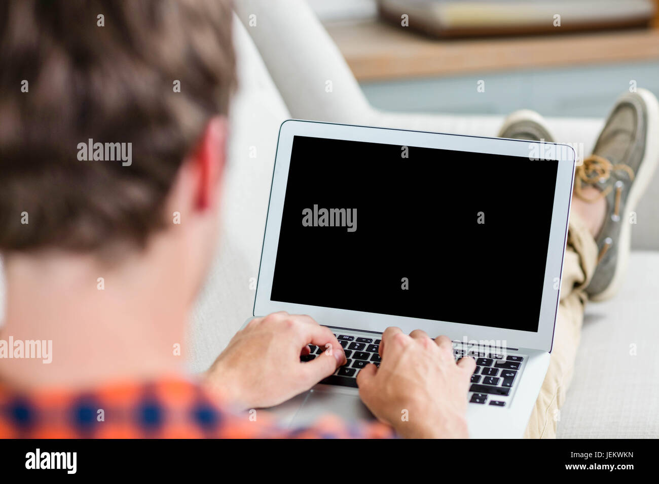 Handsome man using laptop on couch Stock Photo - Alamy