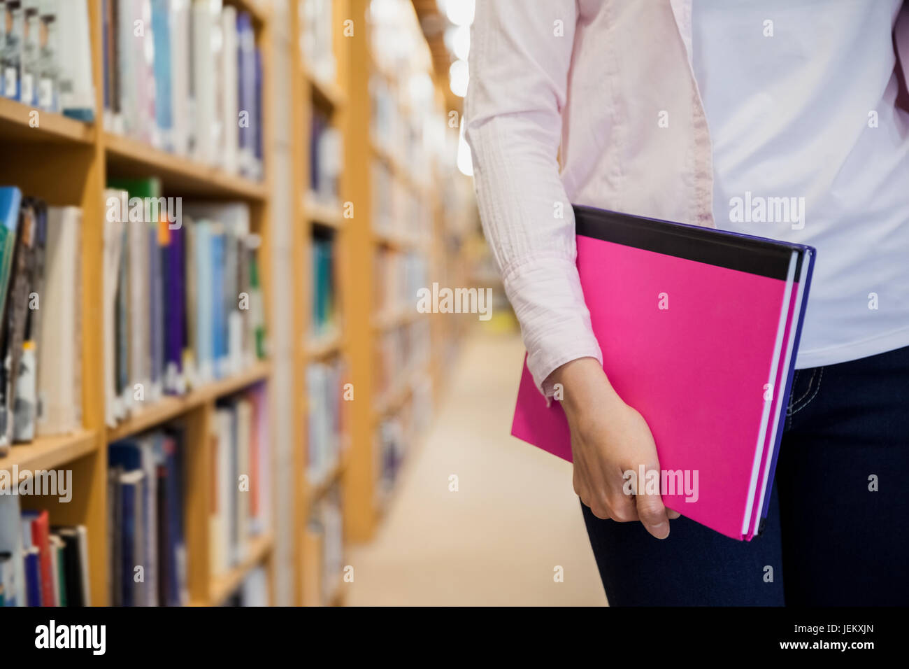 Female student holding textbooks in library Stock Photo - Alamy