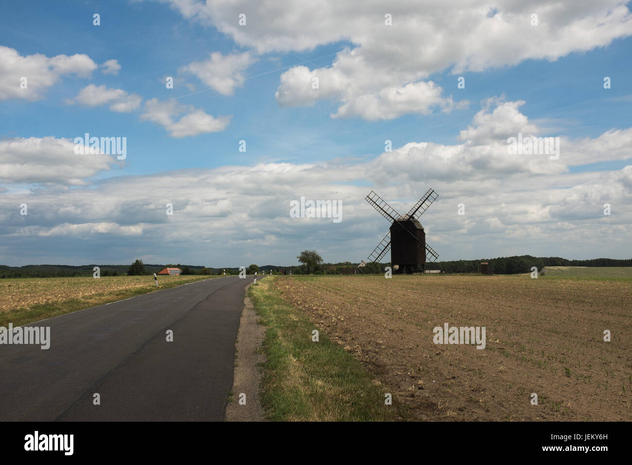 Wooden windmill, field and road - countryside landscape Stock Photo - Alamy