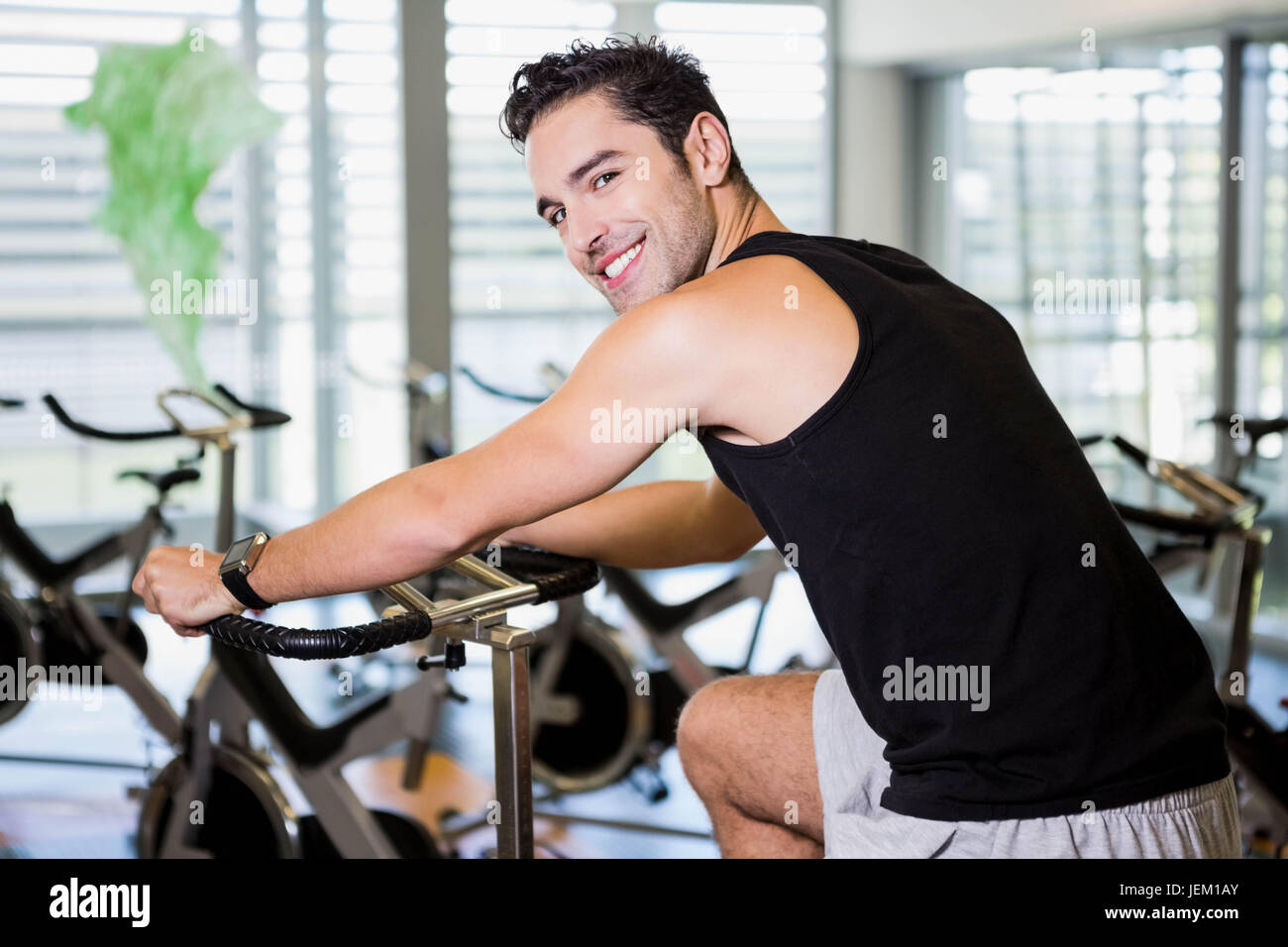 Smiling man using exercise bike Stock Photo - Alamy