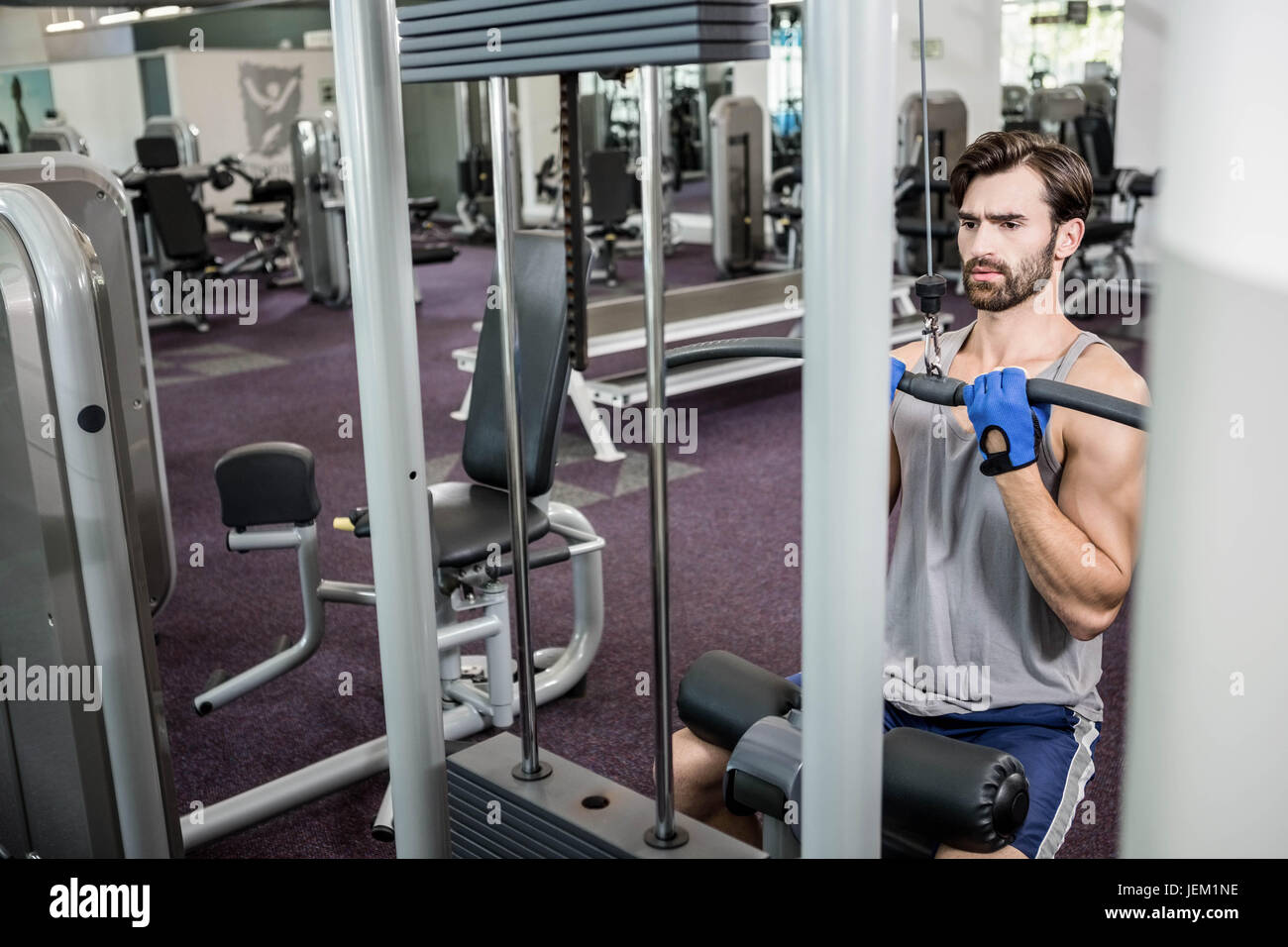 Focused man using weights machine for arms Stock Photo - Alamy