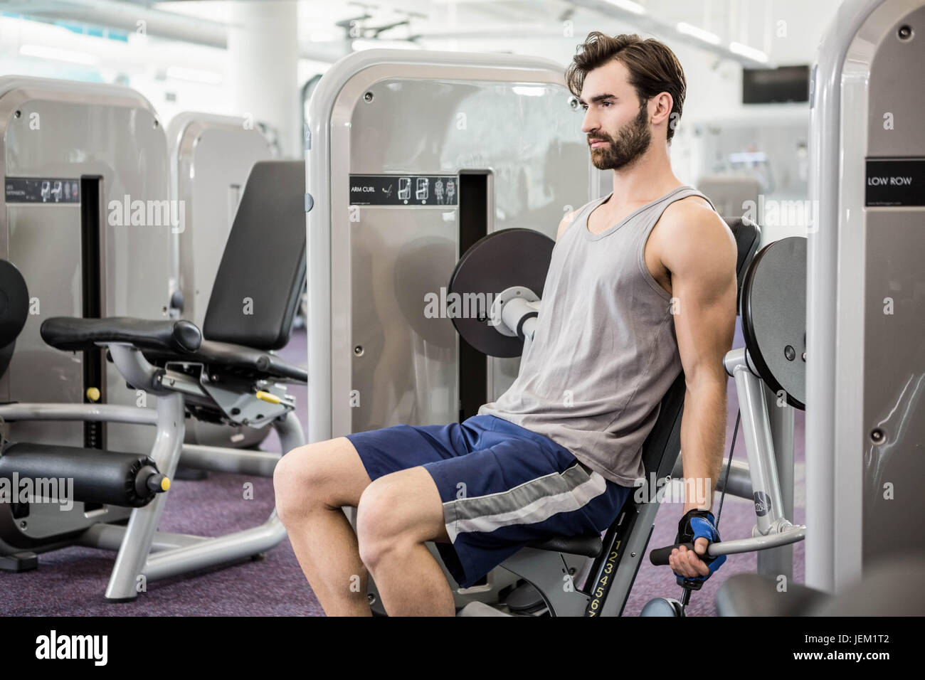 Focused man using weights machine for arms Stock Photo - Alamy