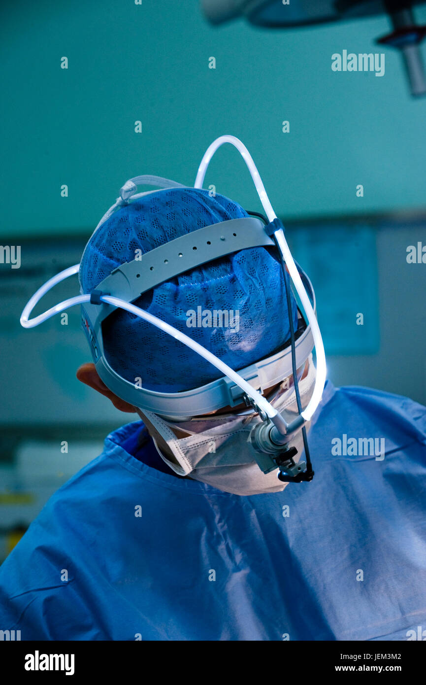 Surgeon operating using a fibre-optic head-light to enable a clear view ...