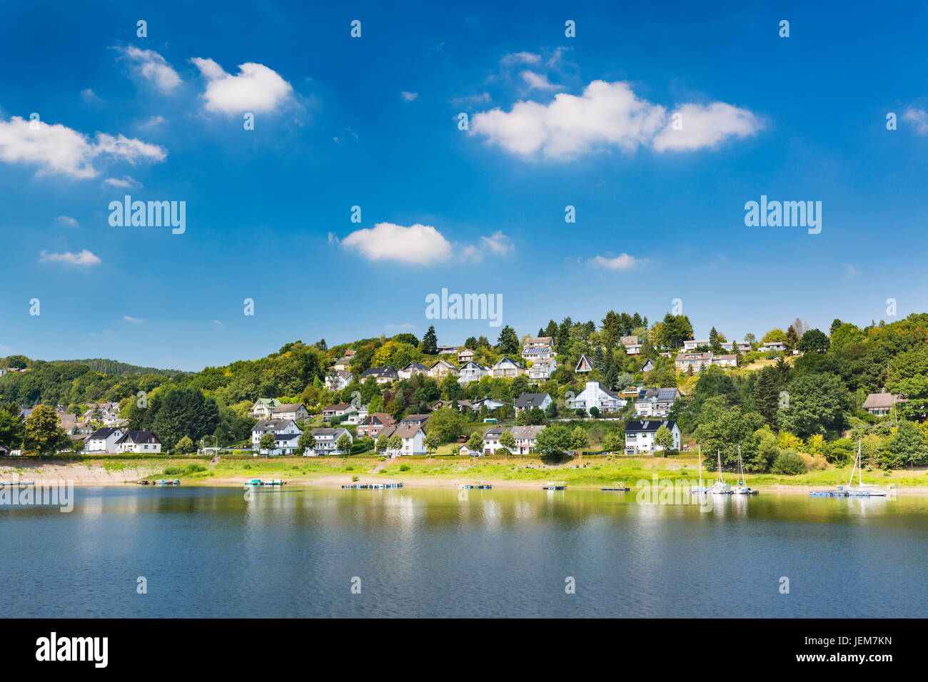 Rurberg village with houses overlooking Lake Rursee with perfect blue ...