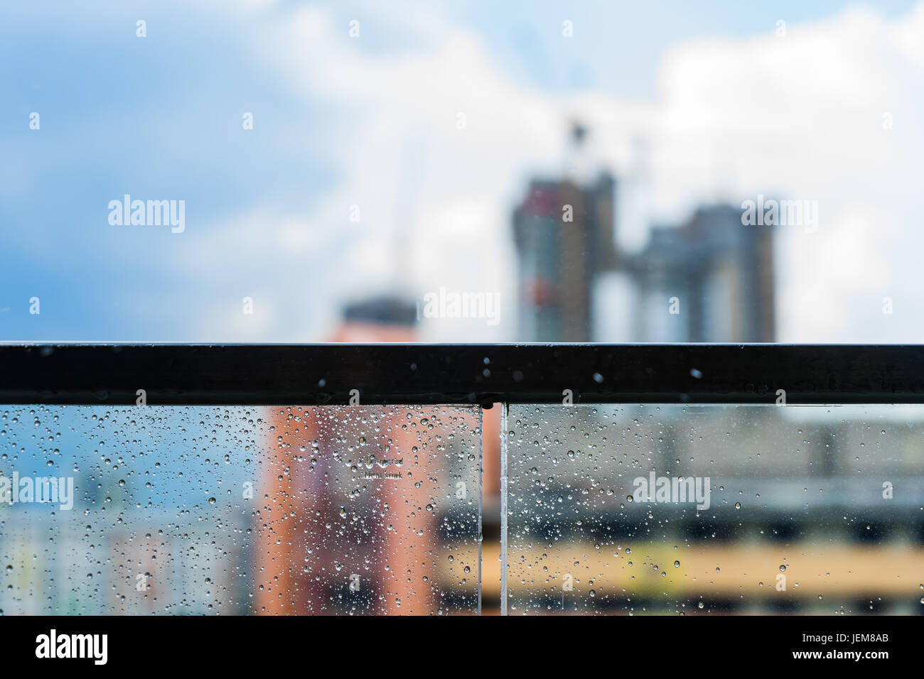 Rain drops on glass balcony, rainy day and construction in background ...