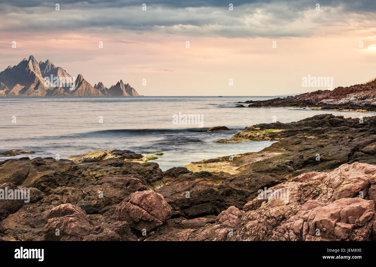 seascape with rocky coast and mountain ridge with high peaks. composite ...
