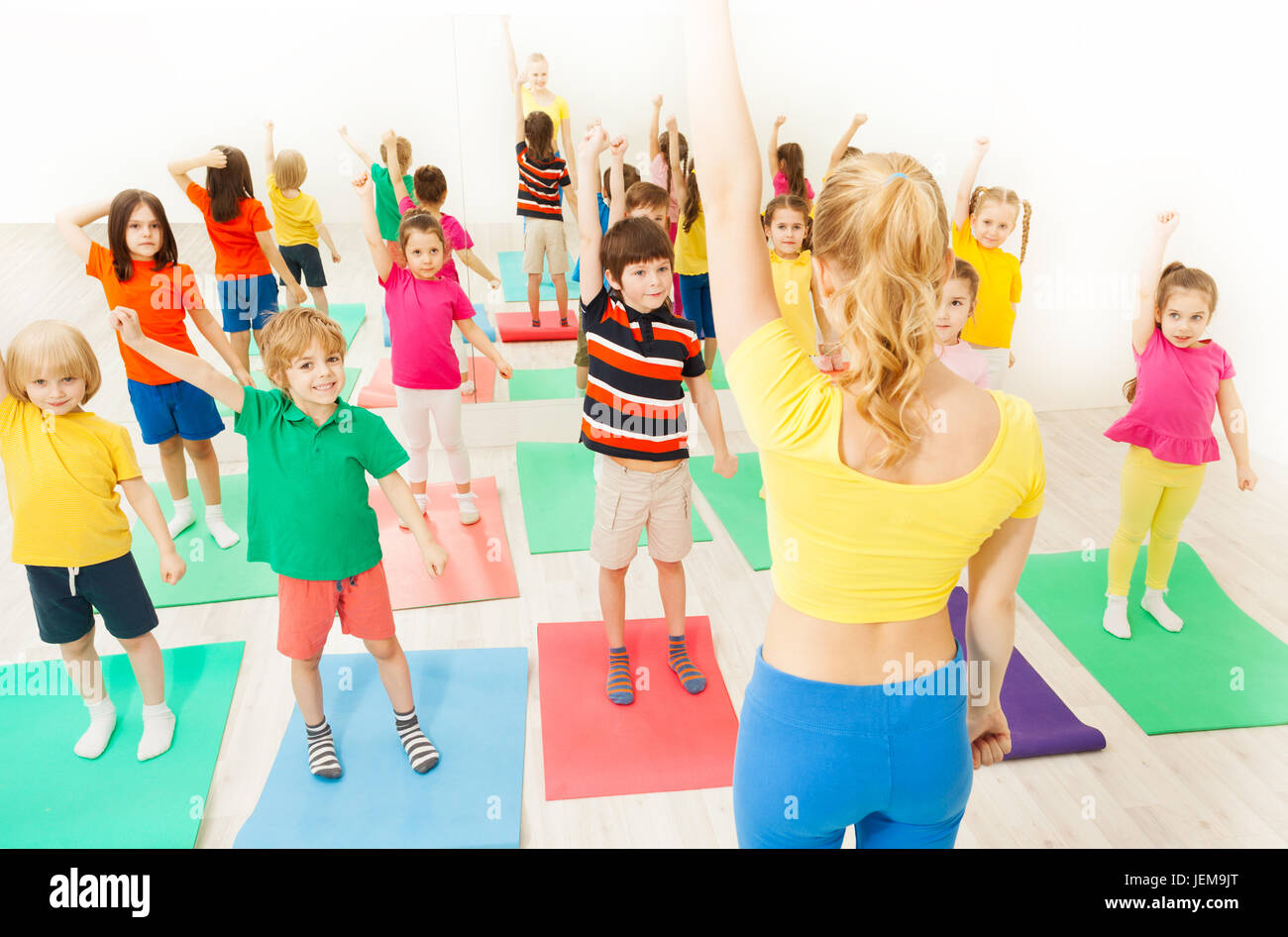 Kids doing gymnastic exercises with female coach Stock Photo - Alamy