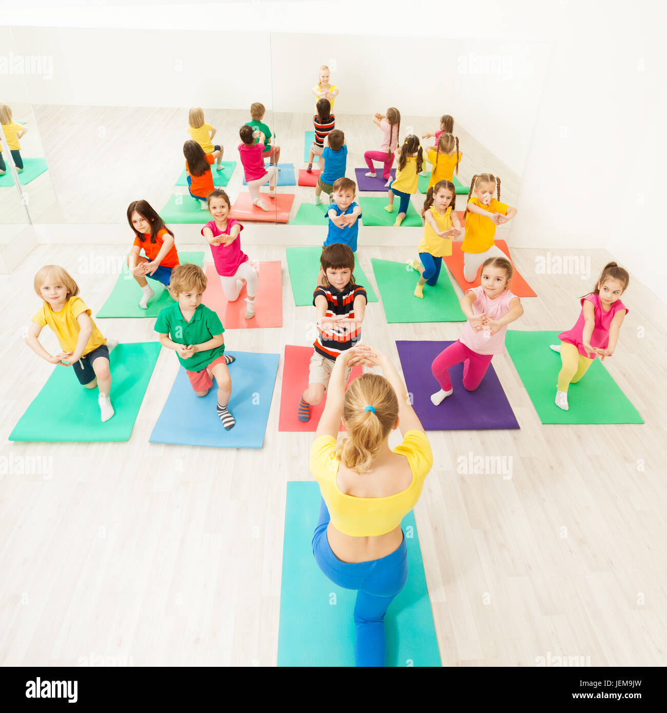 Happy kids doing kneeling exercises in gym Stock Photo - Alamy