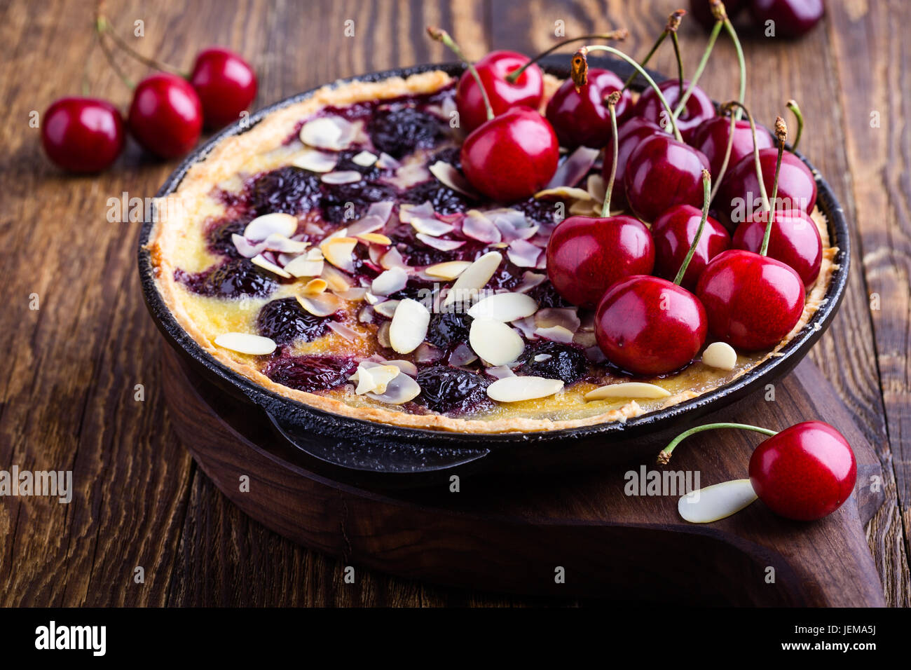 Homemade sweet cherry tart served in rustic cast iron skillet and fresh ...