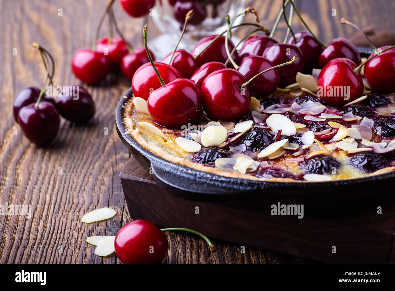 Homemade sweet cherry tart served in rustic cast iron skillet and fresh ...
