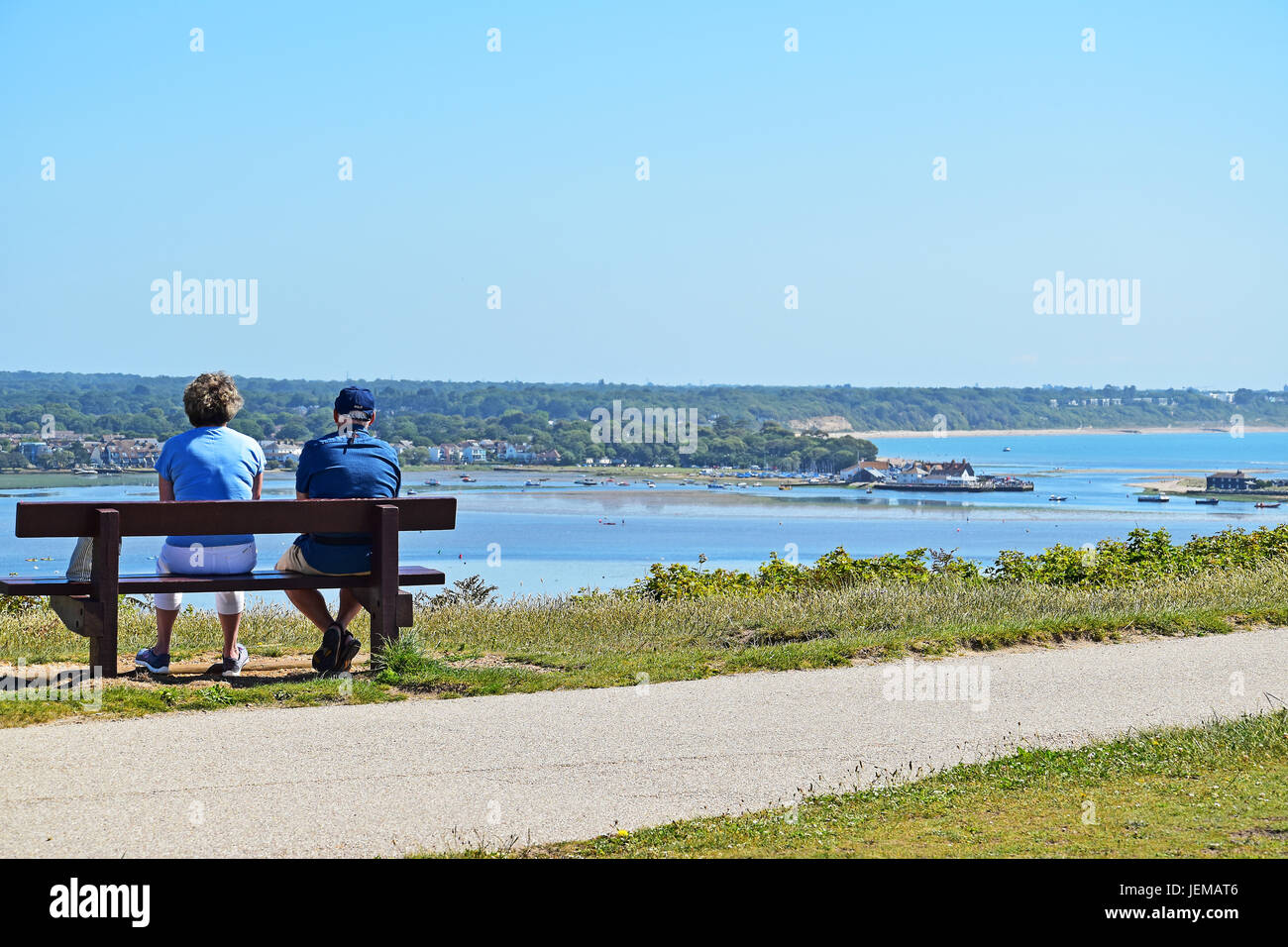 Couple sitting on bench enjoying the view across Christchurch harbour ...