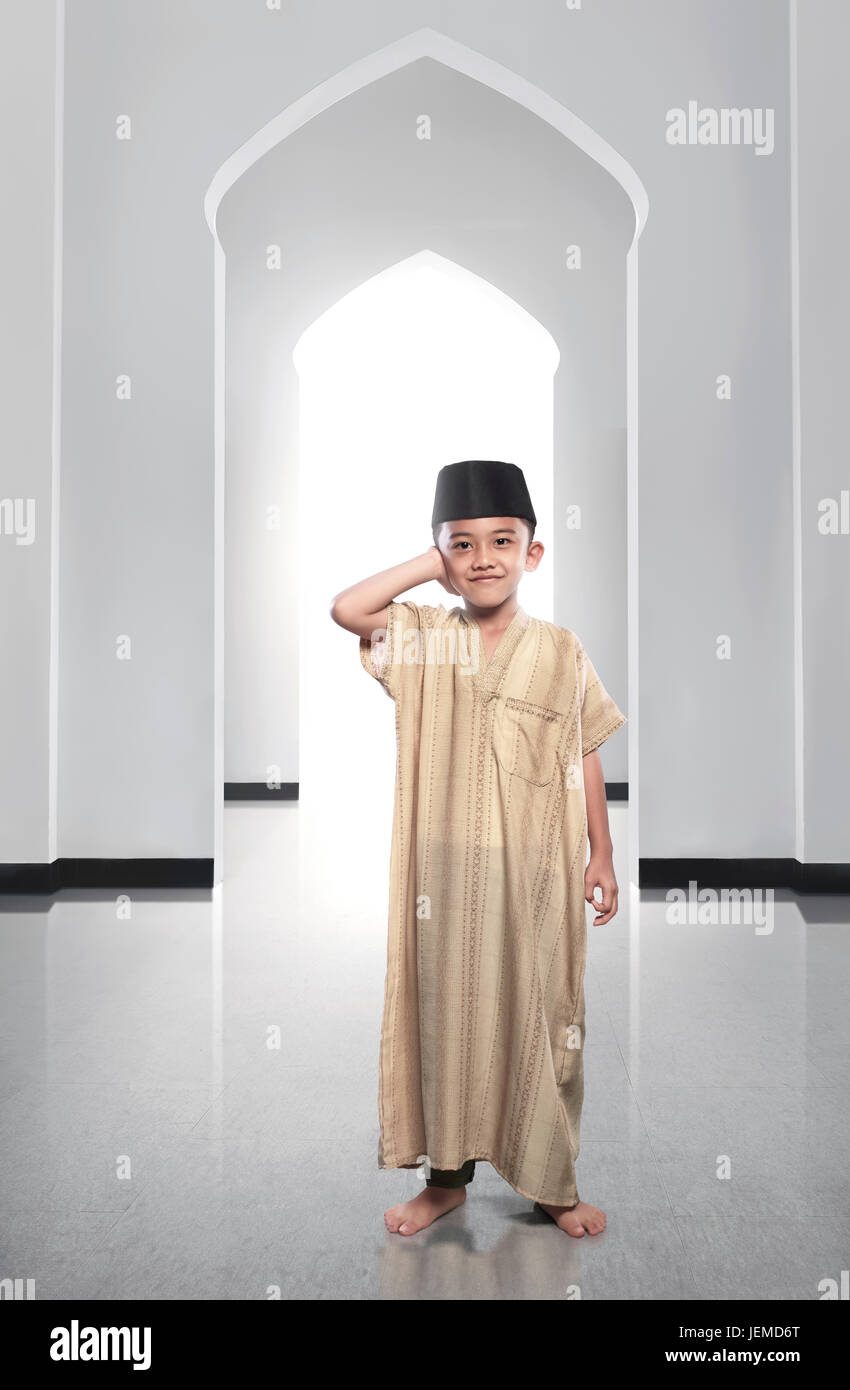 Cheerful asian muslim kid wearing traditional dress praying on the ...