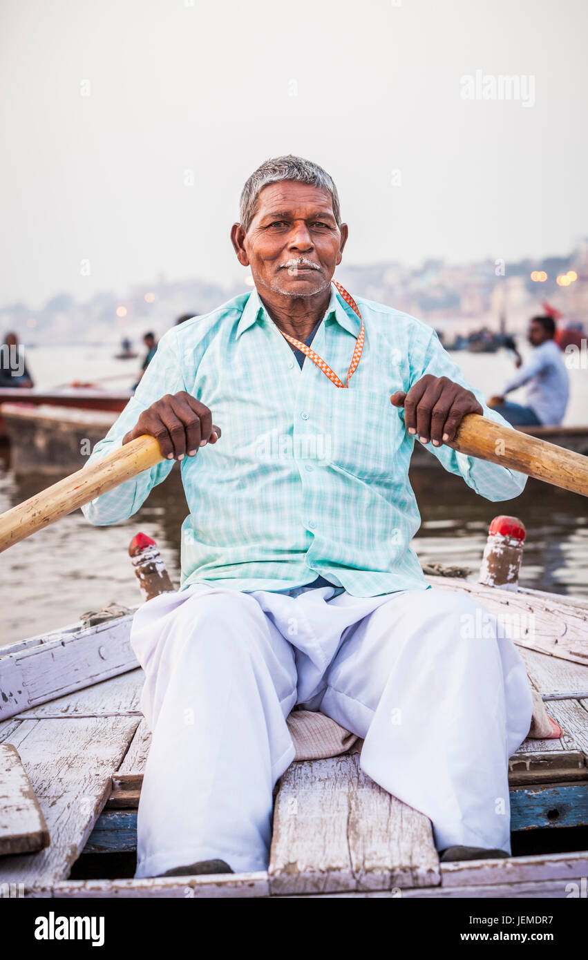 A Indian man rowing a boat for tours on the Ganges river, Varanasi ...