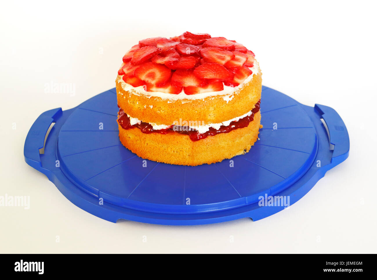 A homemade Victoria sponge on a blue cake stand against a white ...
