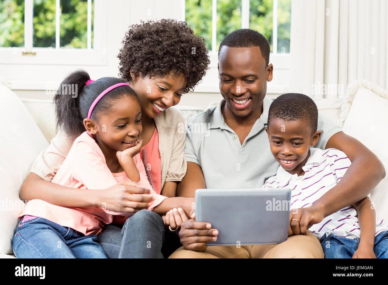 Happy family using tablet on the sofa Stock Photo - Alamy
