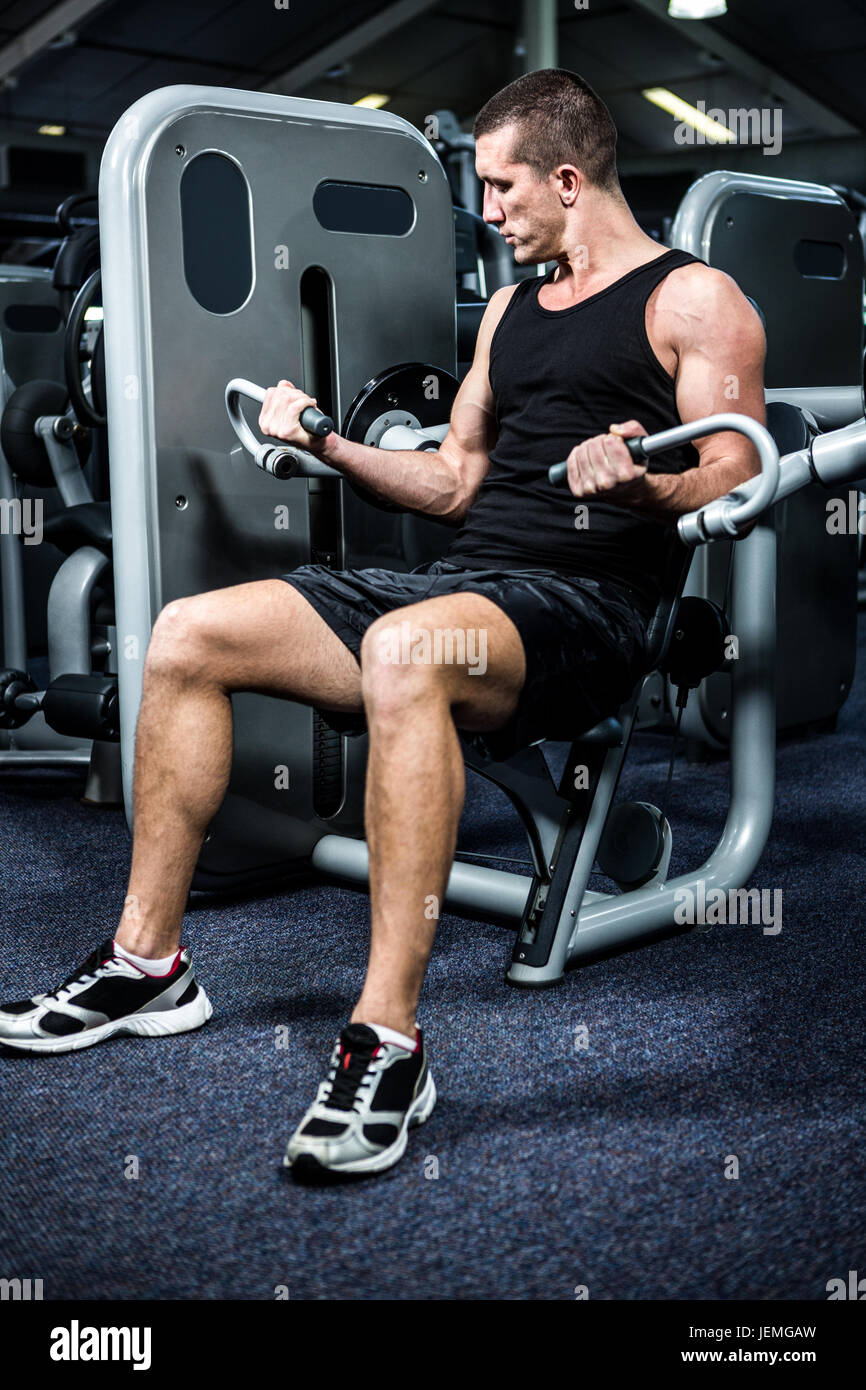 Serious muscular man using exercise machine Stock Photo - Alamy