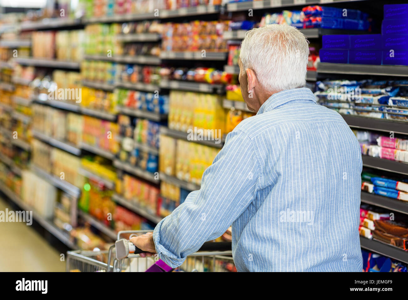 Rear view of senior man pushing trolley Stock Photo - Alamy