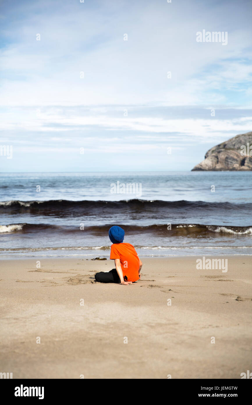 Boy sitting on sandy beach Stock Photo - Alamy