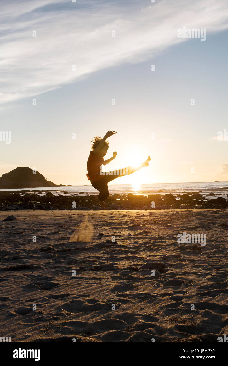 Boy jumping on beach at sunset Stock Photo - Alamy