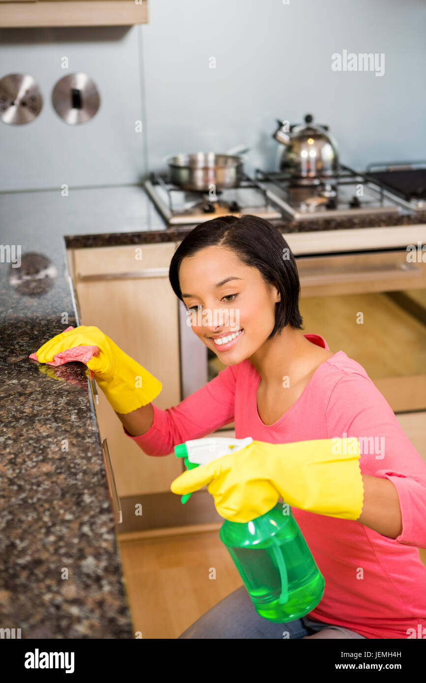 Smiling brunette cleaning kitchen counter Stock Photo - Alamy