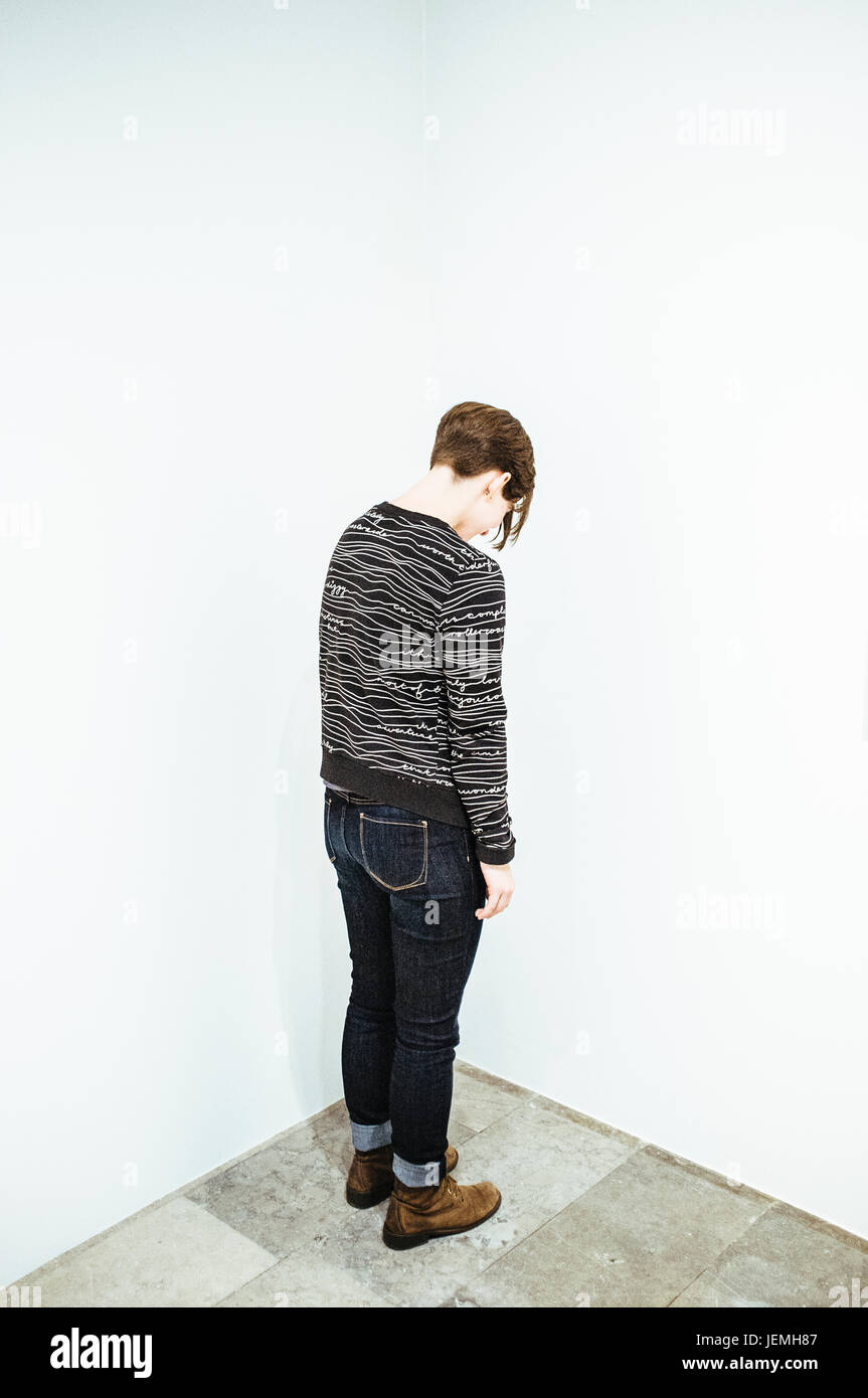 Young woman standing in corner Stock Photo - Alamy