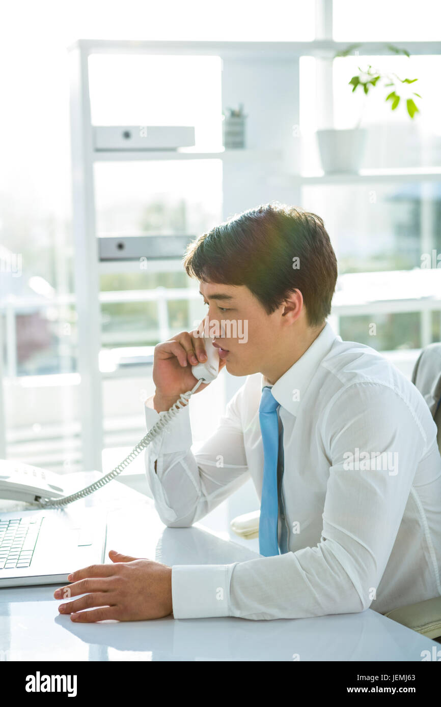 Busy asian businessman answering the phone Stock Photo - Alamy