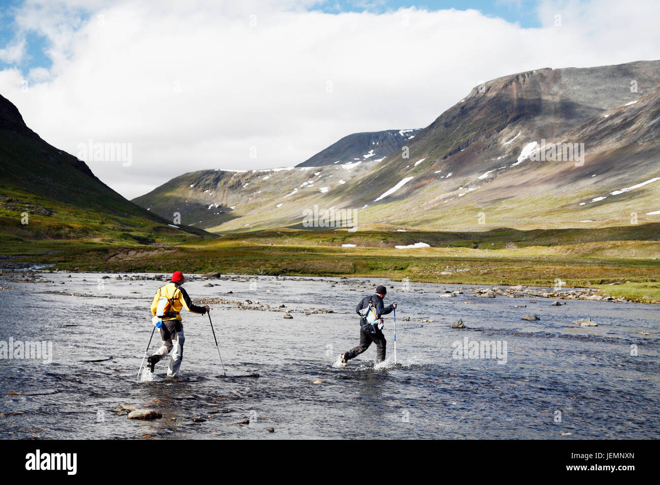 Hikers crossing mountain river Stock Photo - Alamy