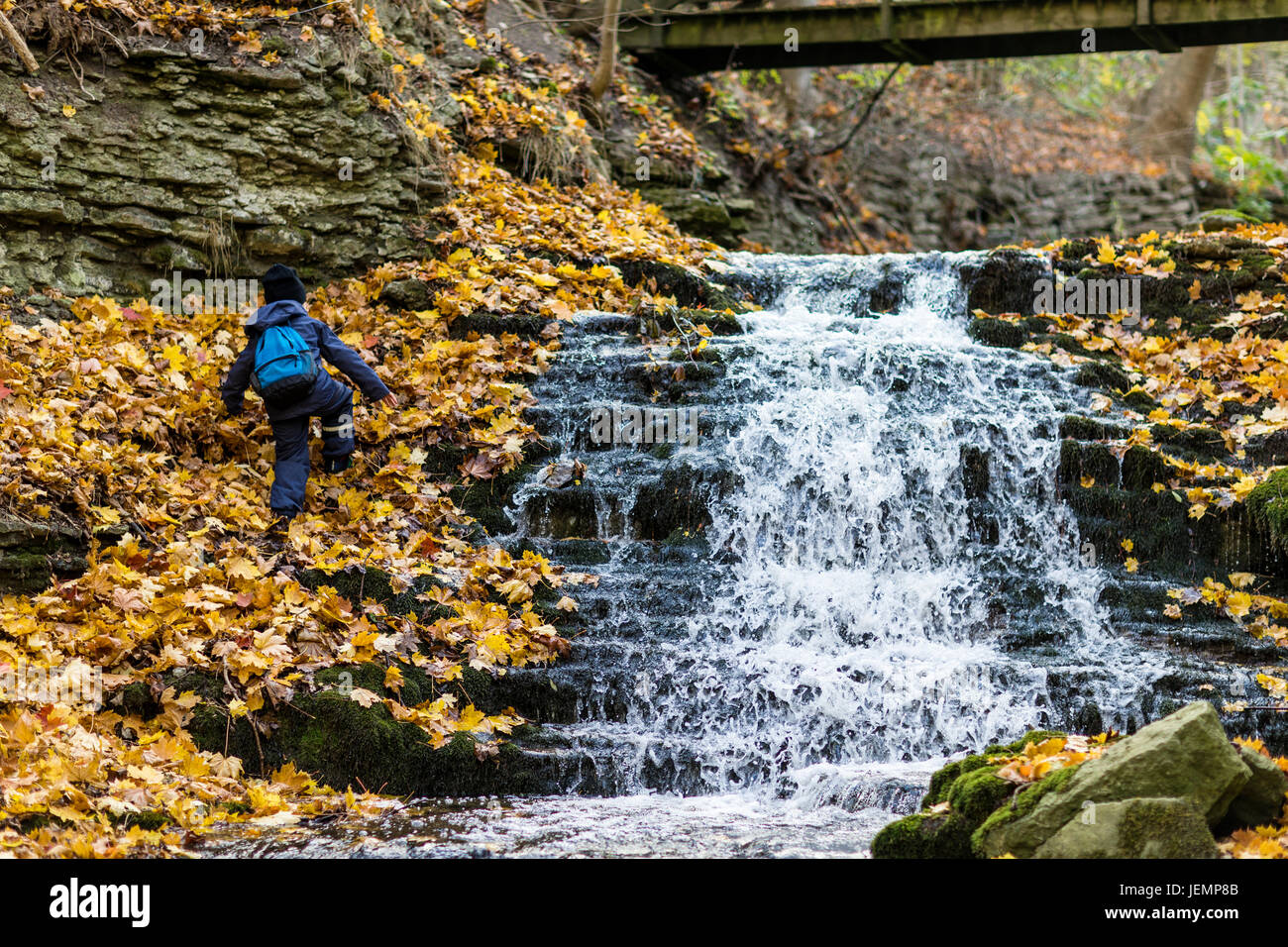 Boy walking at waterfall Stock Photo - Alamy