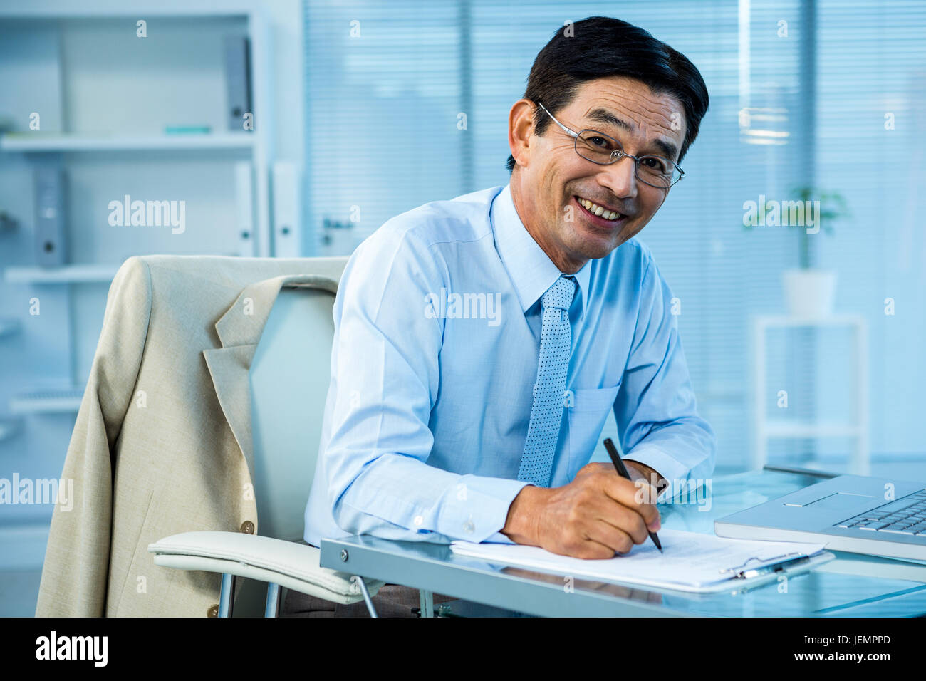 Smiling asian businessman writing a report Stock Photo - Alamy