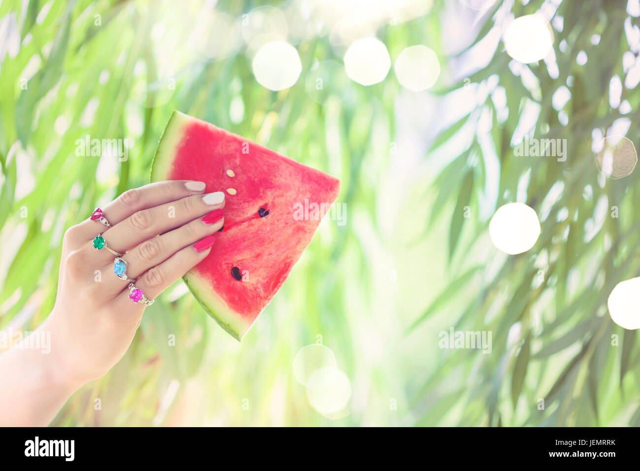 Beautiful hand with many rings and sweet pink melon Stock Photo - Alamy