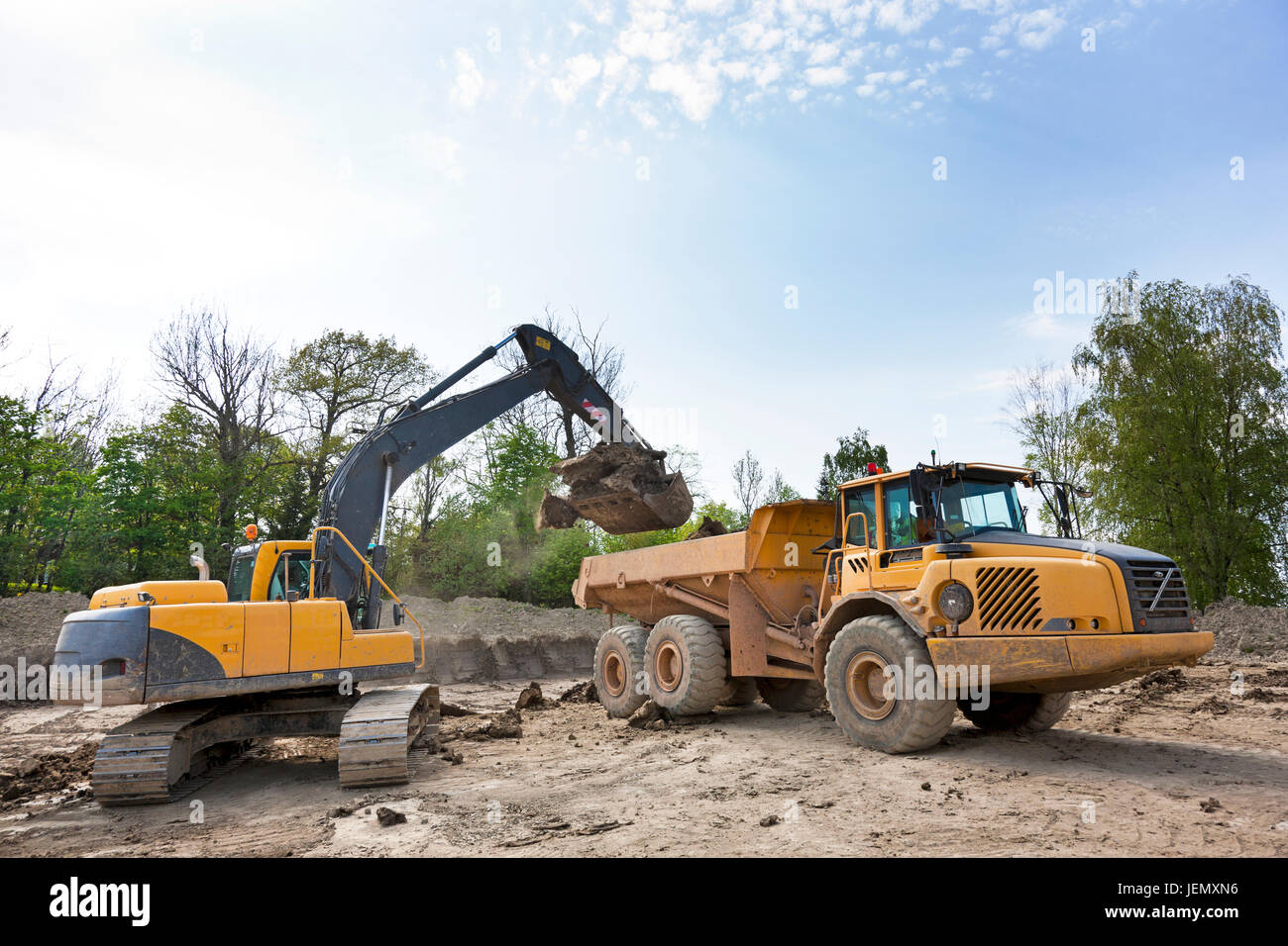 Digger loading dirt on dumper tuck Stock Photo - Alamy