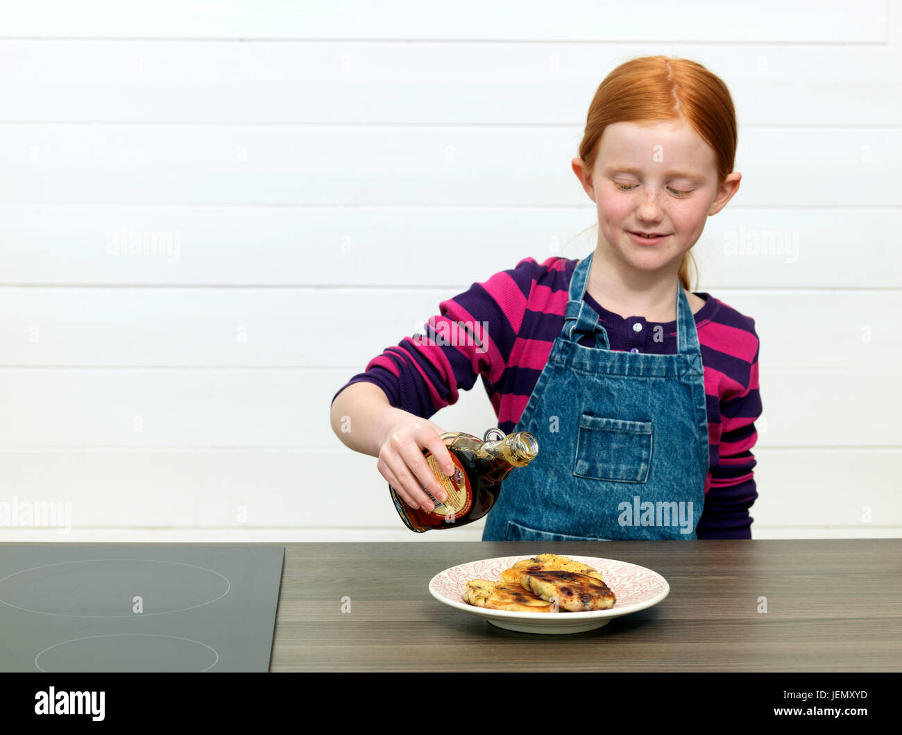 Girl pouring maple syrup on pancakes Stock Photo - Alamy