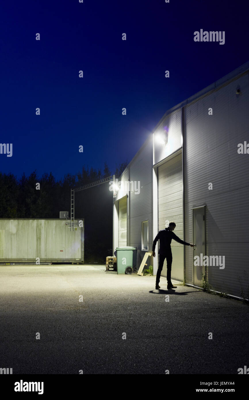 Man opening warehouse back door at night Stock Photo - Alamy