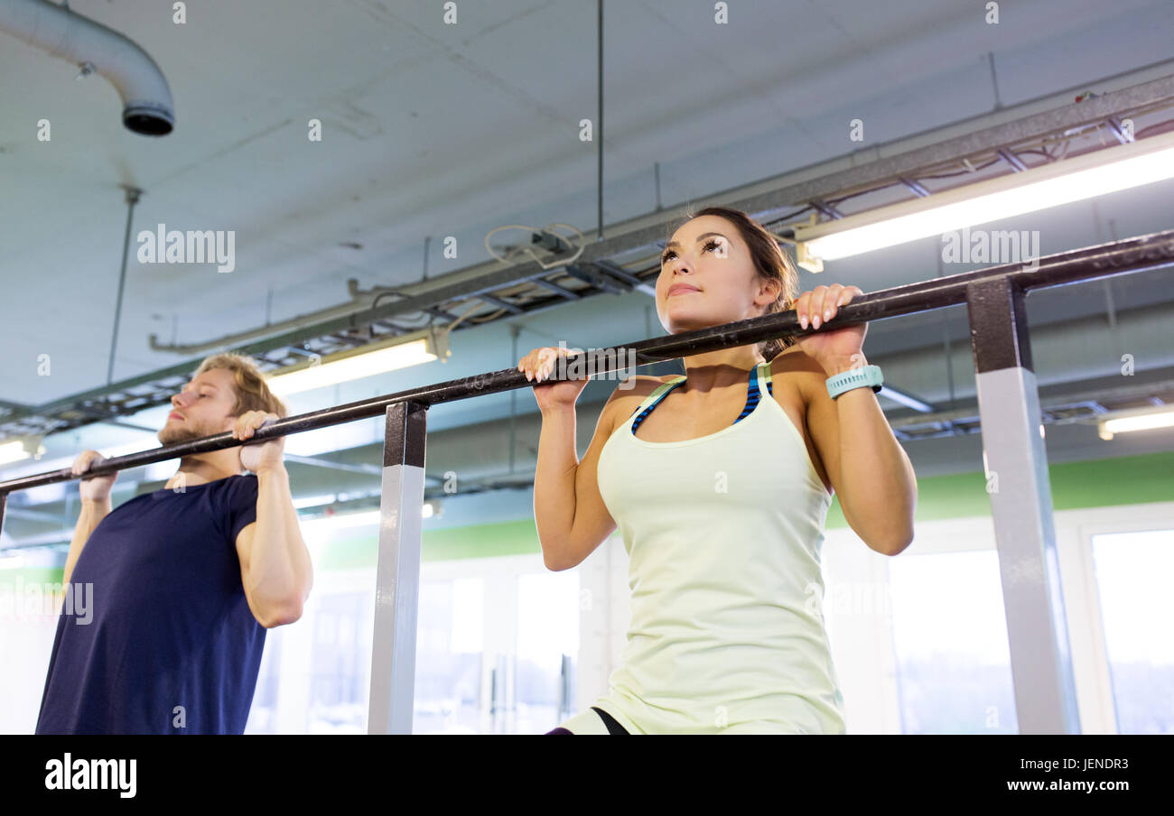 couple doing pull-ups at horizontal bar in gym Stock Photo - Alamy