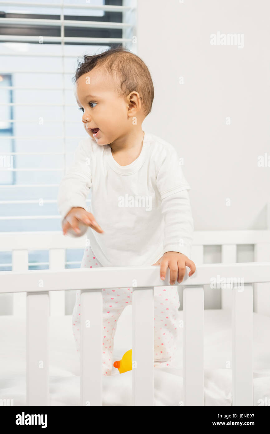 Cute baby standing in the crib Stock Photo - Alamy