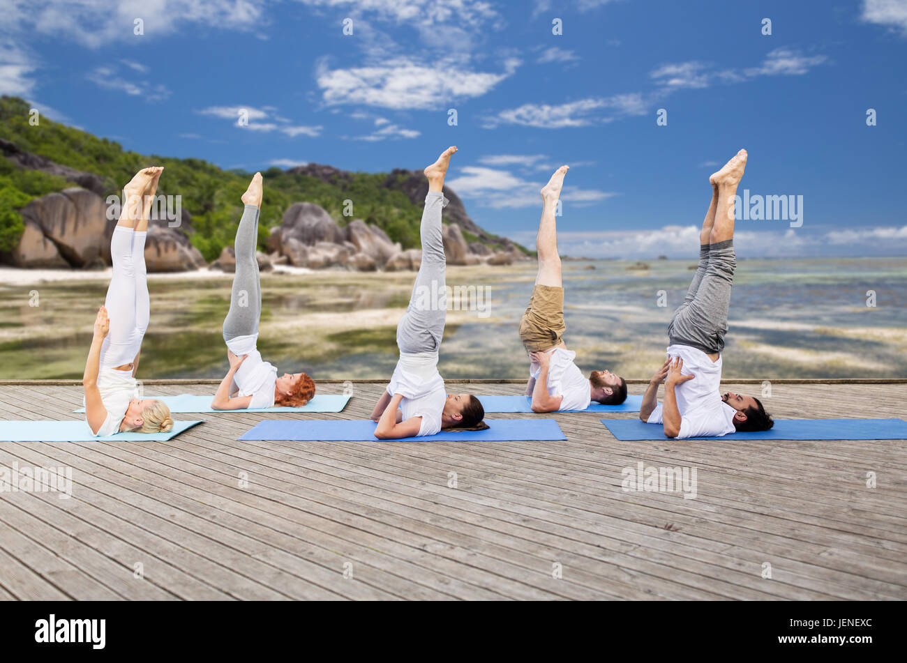 people making yoga in shoulderstand pose on mat Stock Photo - Alamy