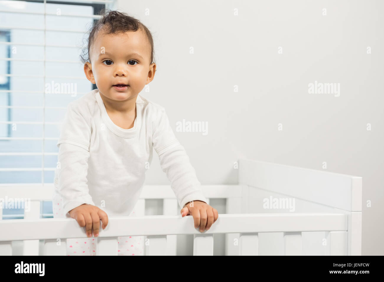 Cute baby standing in the crib Stock Photo - Alamy