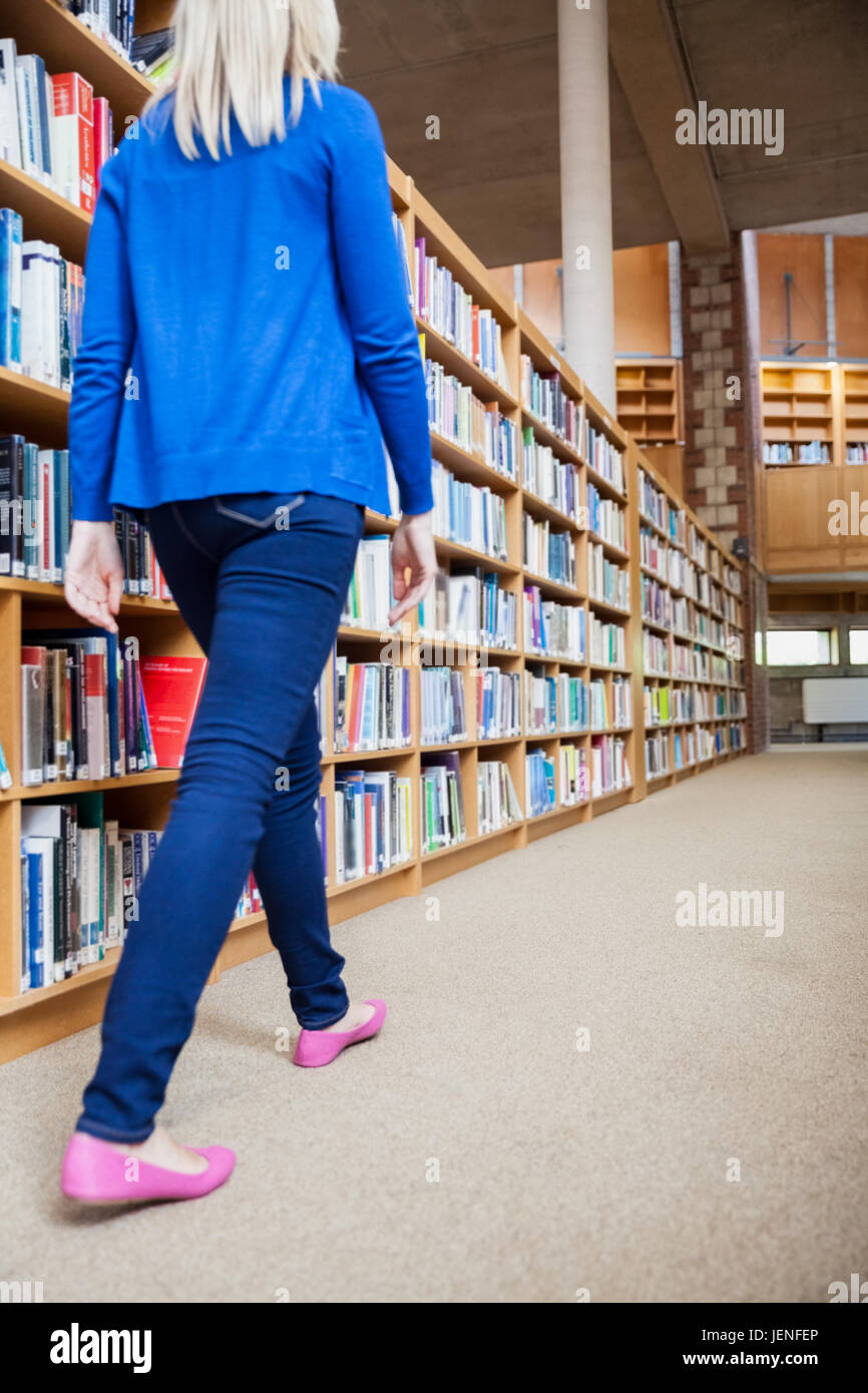 Female student walking in the library Stock Photo - Alamy