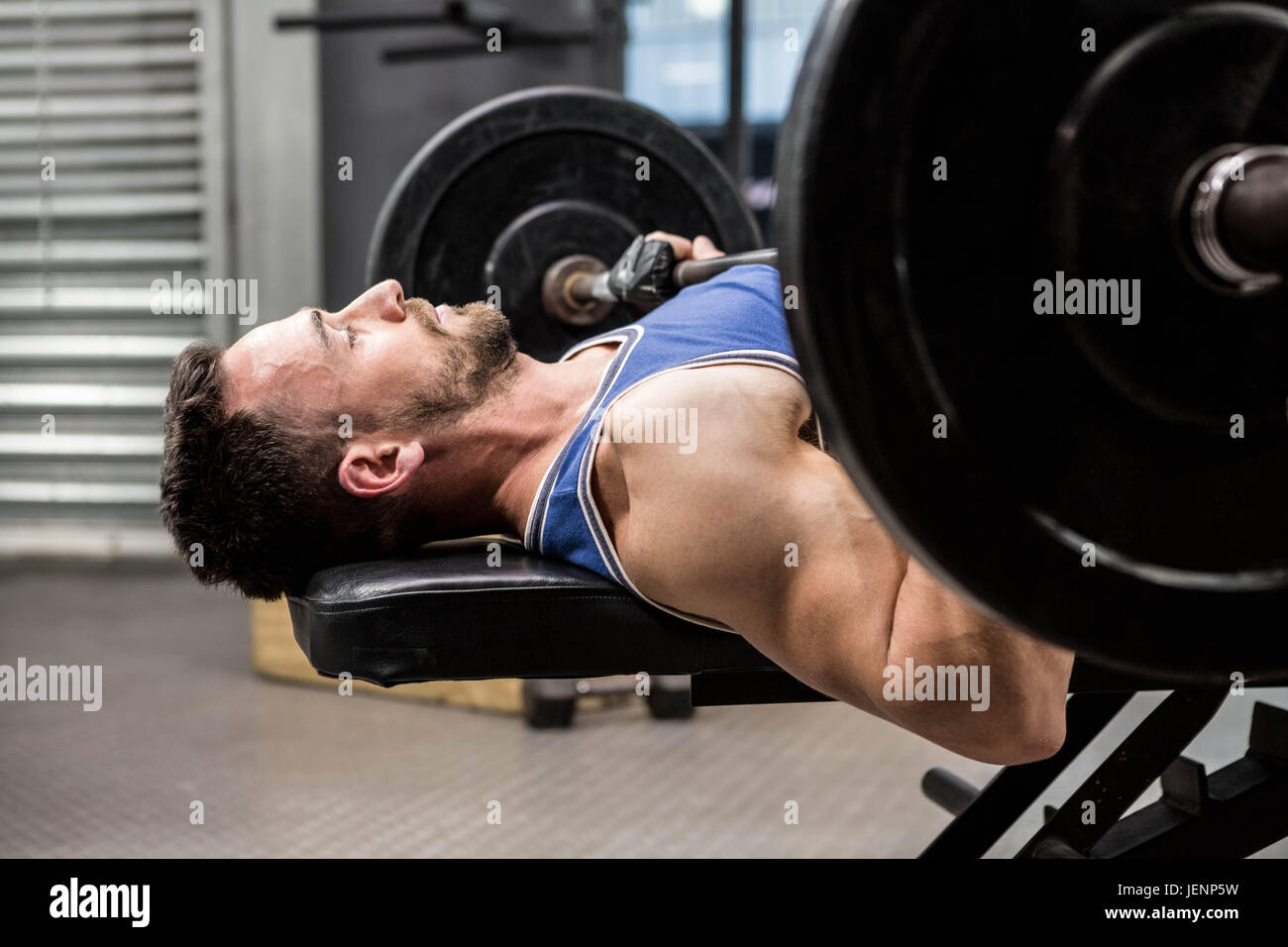 Muscular man on bench lifting barbell Stock Photo - Alamy
